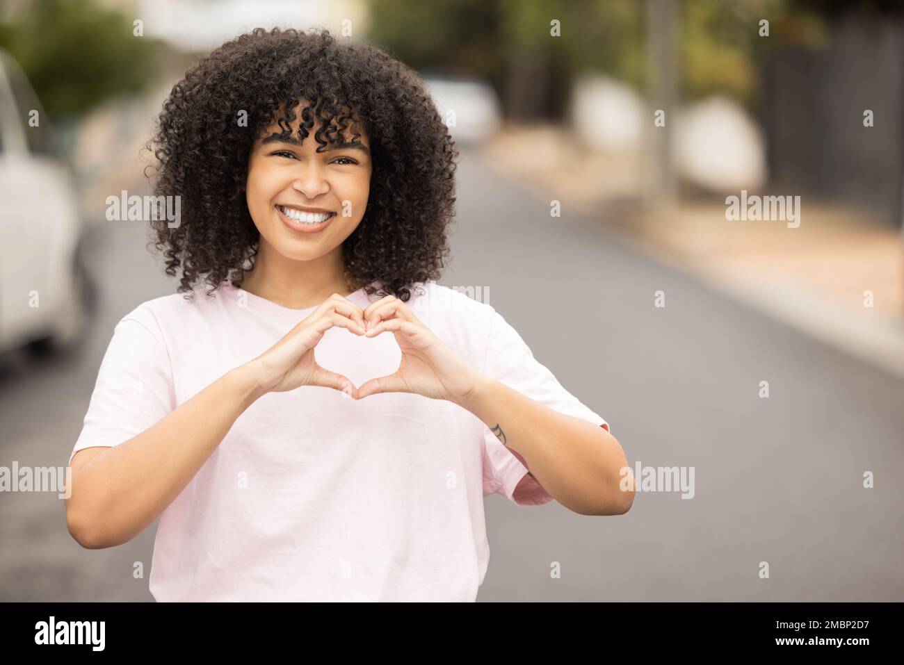 Heart hands sign, black woman and portrait of a young person in a urban ...