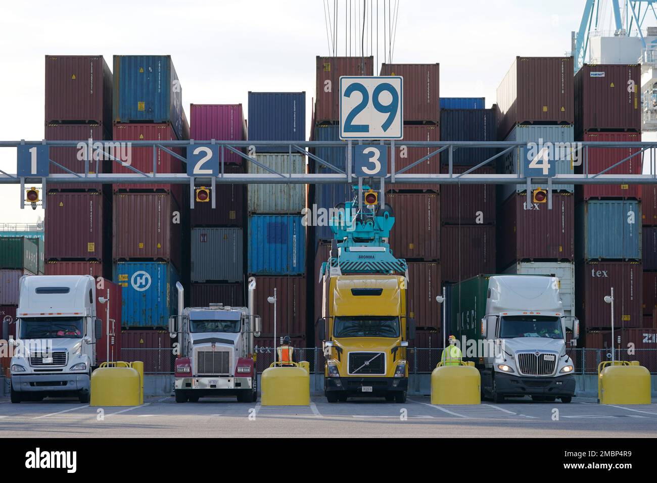 FILE - Trucks line up to have containers loaded from a stack at the ...