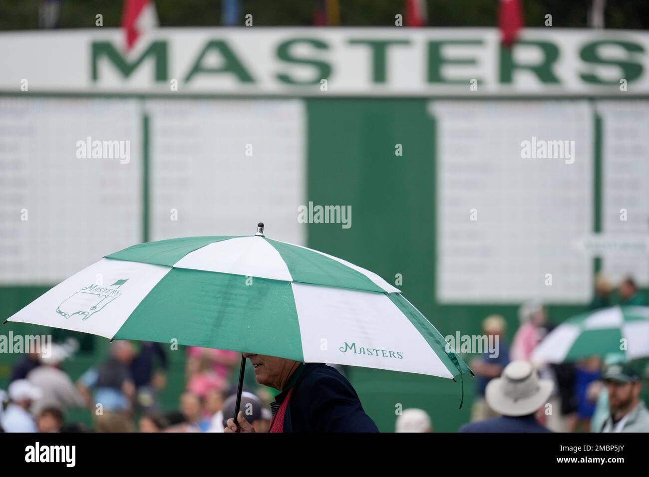 A spectator walks in the rain past the main leaderboard during the ...