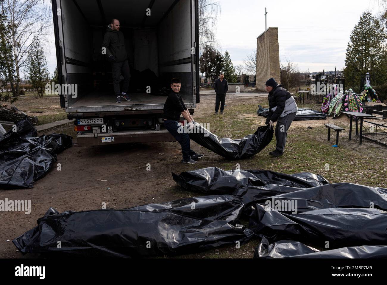 Cemetery workers load the corpses of civilians killed in Bucha, to be ...