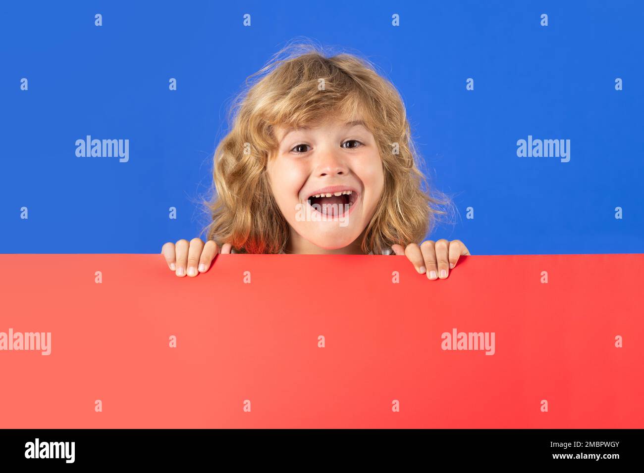 Excited kid boy on studio isolated background. Child hold red blank ...