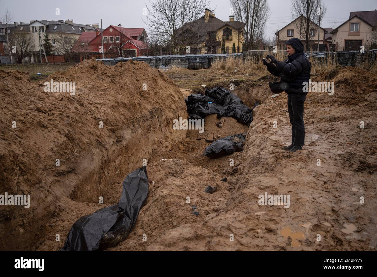 A journalist takes video of a mass grave in Bucha, on the outskirts of ...