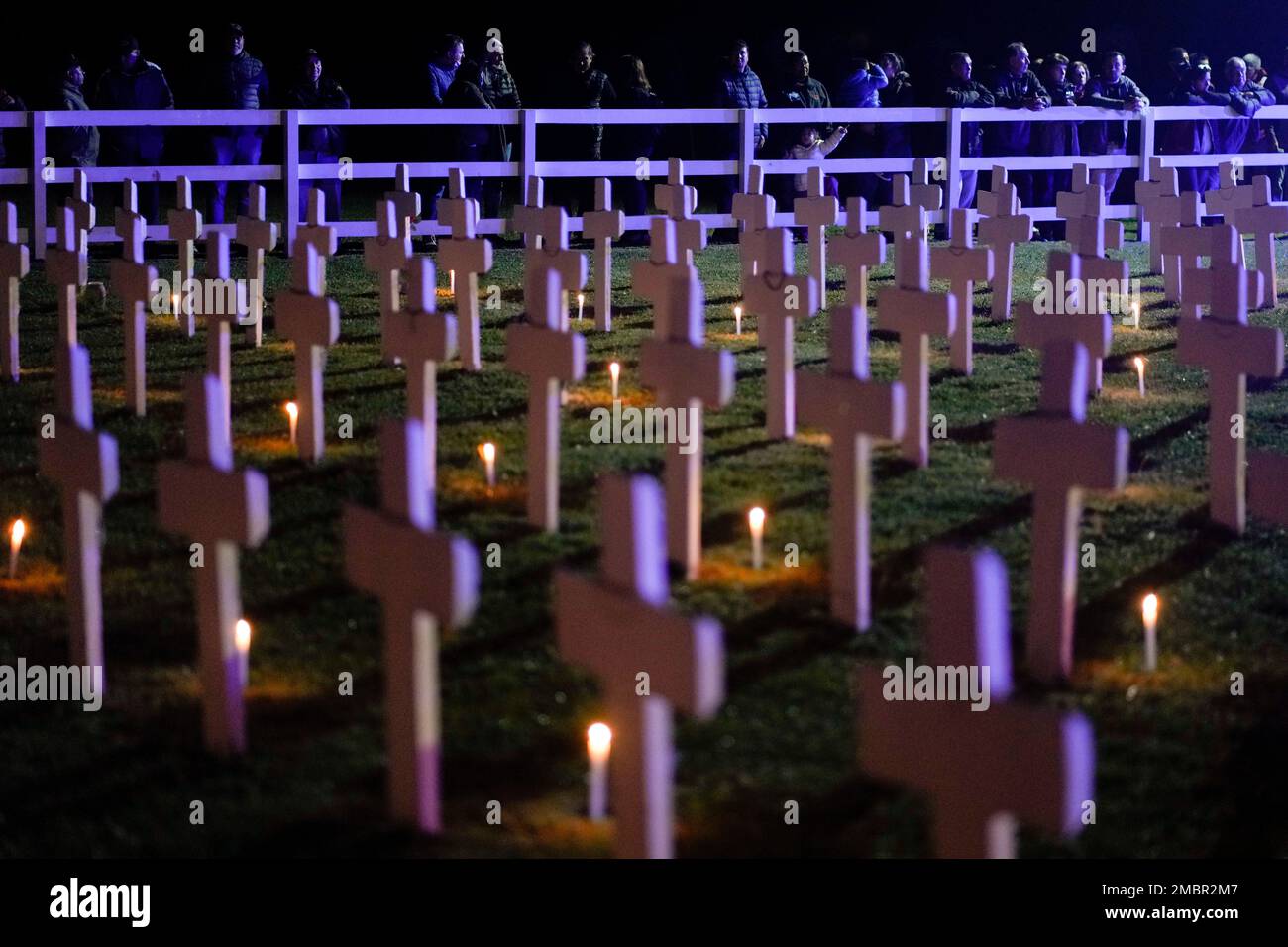 Visitors gather on a field lined with crosses remembering the ...