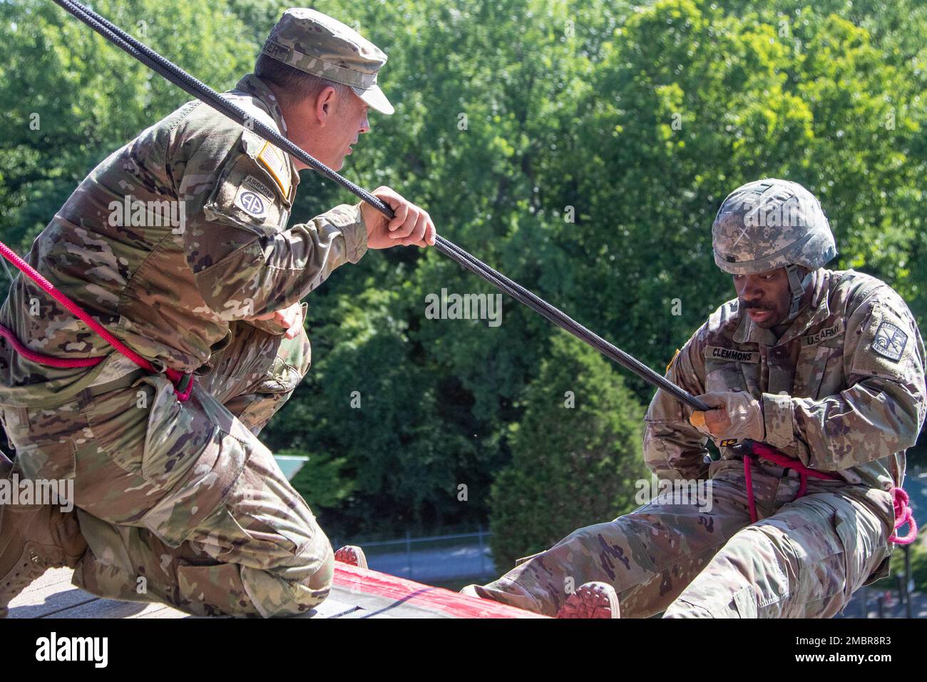 Master Sgt. Eric Harder, left, a rappel master, guides a cadet down the ...