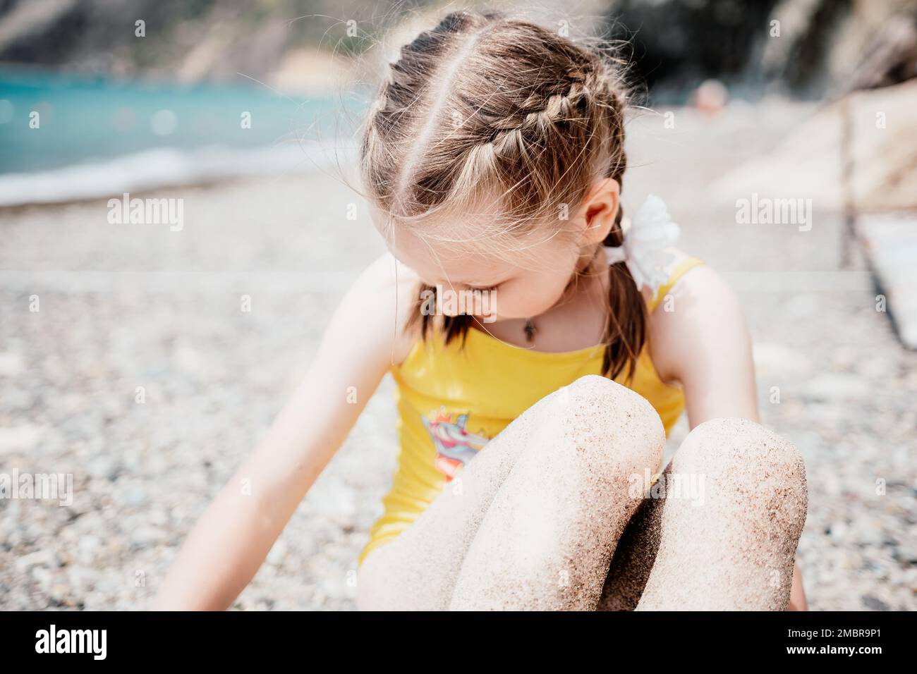 Cute little girl running along the seashore against a clear blue sea ...