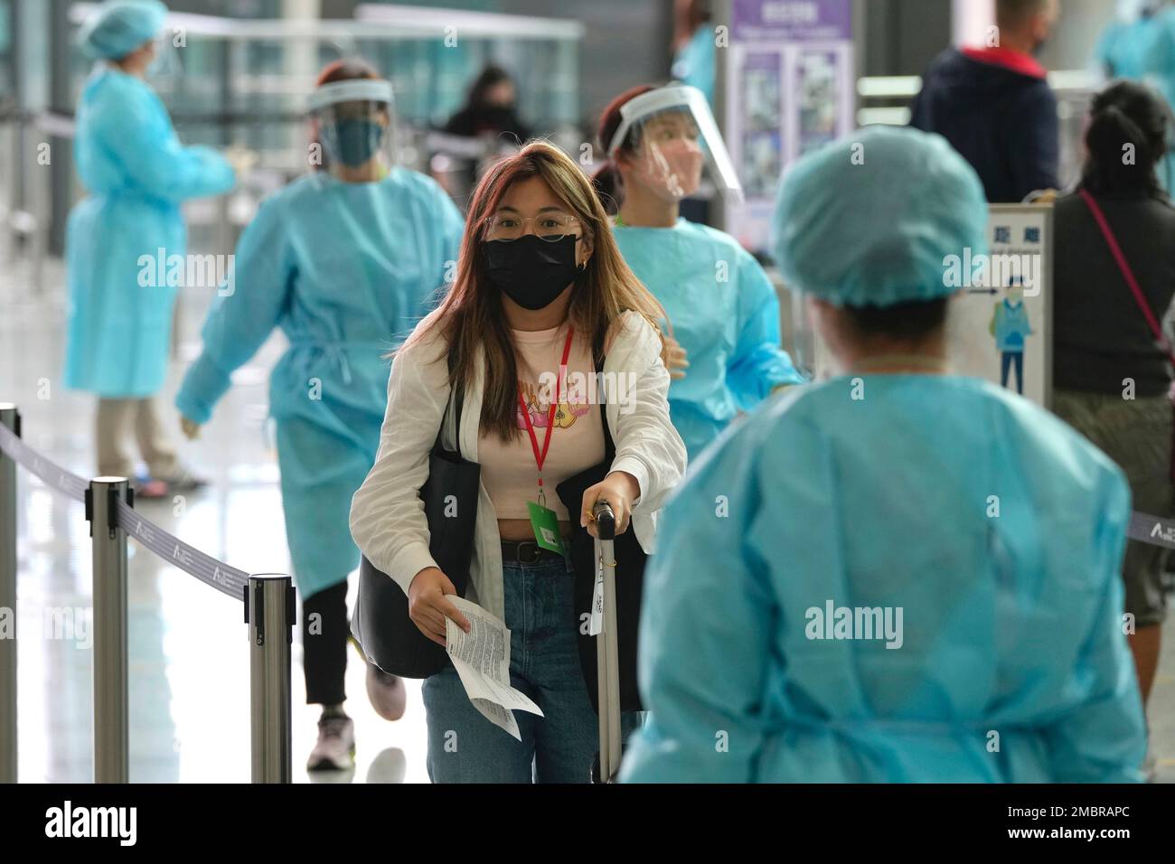 Workers wearing gowns, masks and gloves, direct arriving passengers from Manila for buses to ...