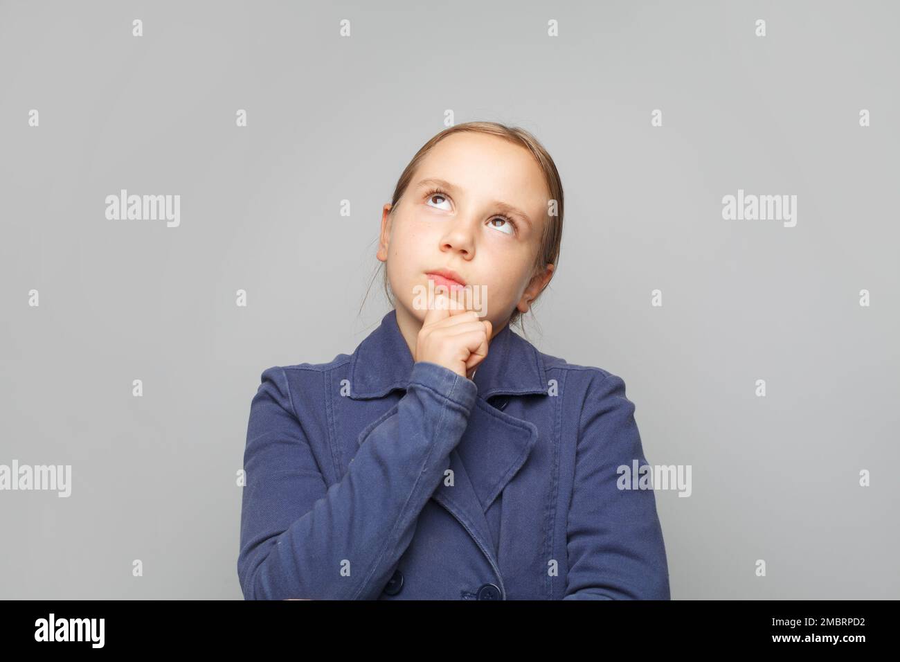 Cute little child school girl thinking and looking up against white ...