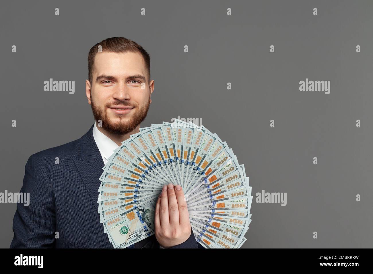 Smart businessman holding money fan on grey background. Business win ...