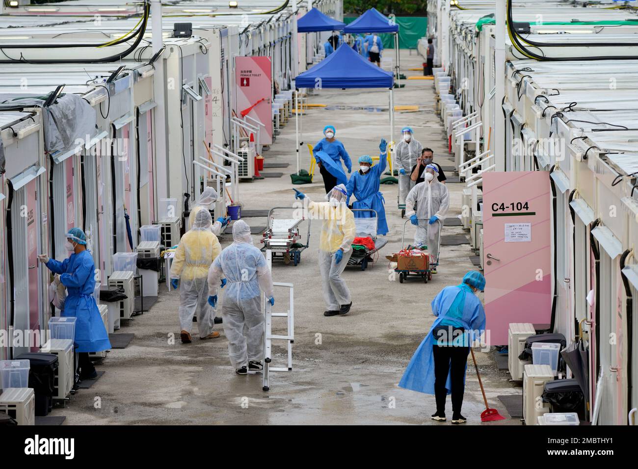 Workers wearing personal protective equipment, work at the makeshift ...