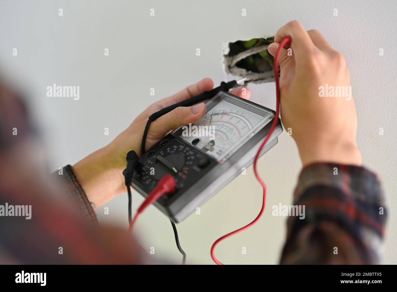 Electrician installer using a multimeter to test power line current in ...