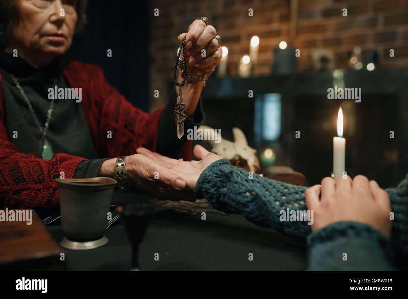 Mature witch using crystal pendulum to predict future for client Stock ...