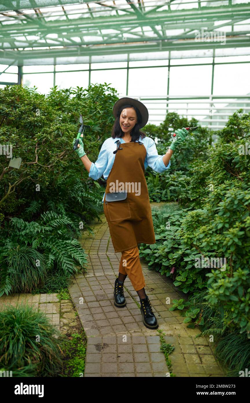 Happy gardener florist posing for camera with garden tools over ...