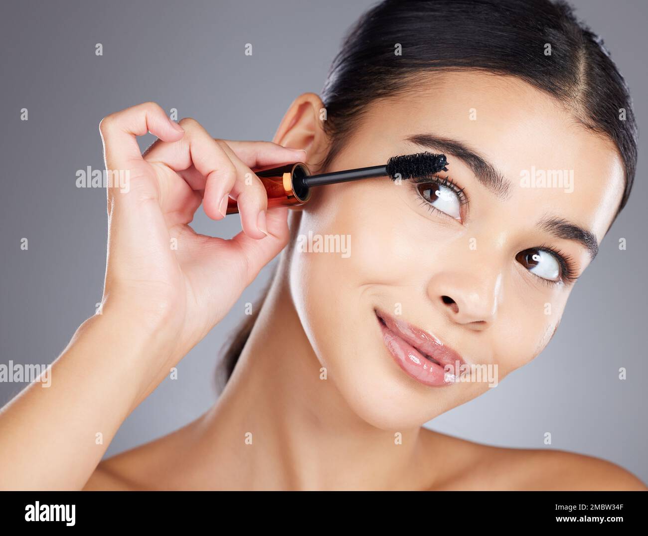 Beauty makeup, face and woman with mascara in studio isolated on gray ...