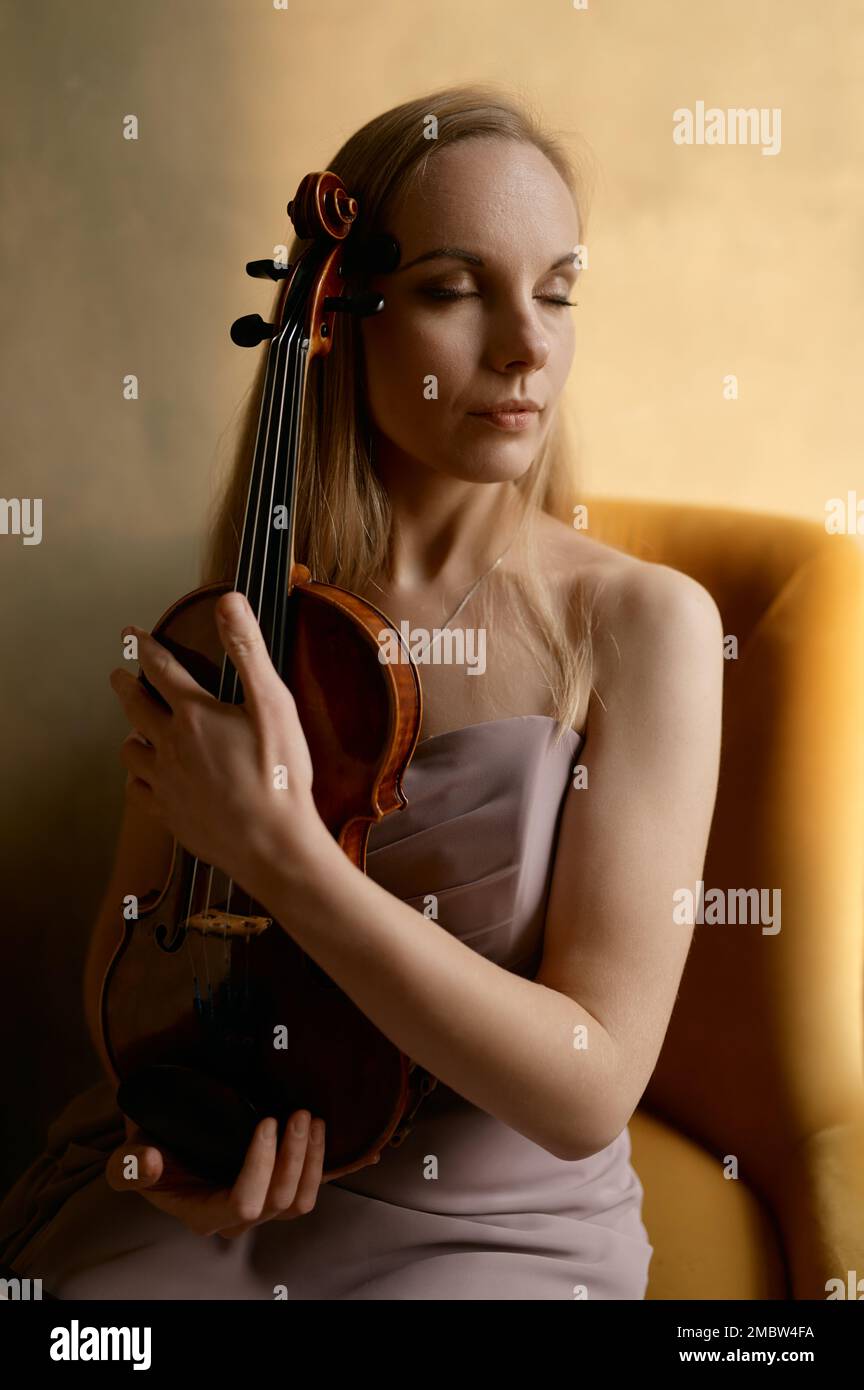 Beautiful young woman hugging violin with her arms Stock Photo - Alamy