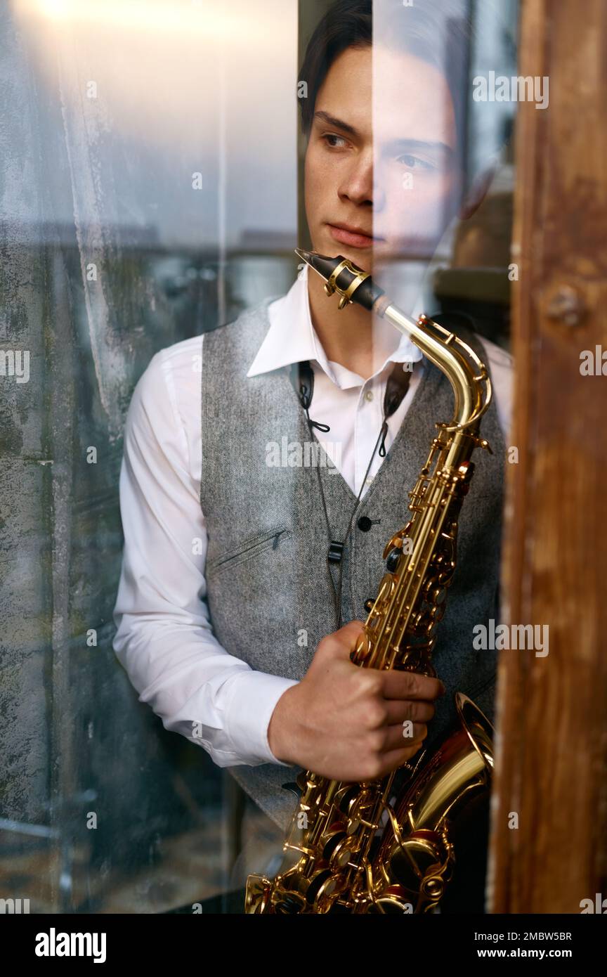 Young man saxophonist with instrument view from window Stock Photo - Alamy