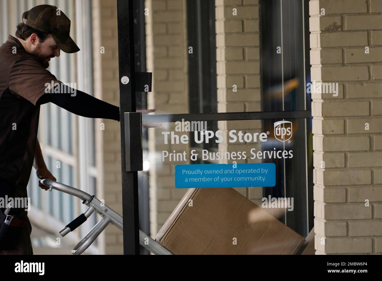 A UPS driver enters a United Parcel Service store with packages in ...