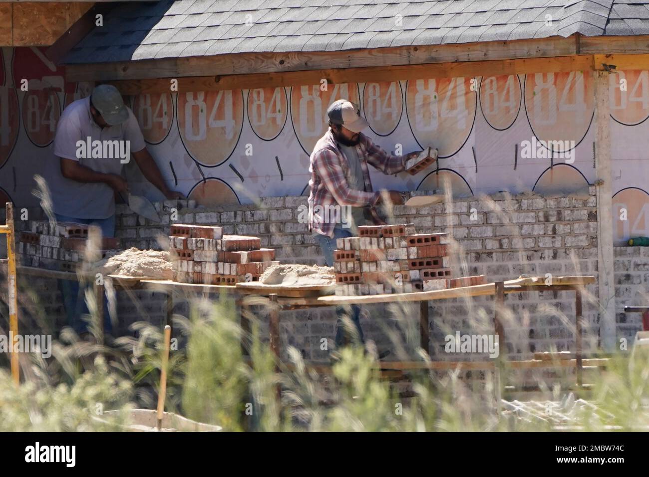 Workers lay a brick wall on a house under construction in Flowood, Miss ...