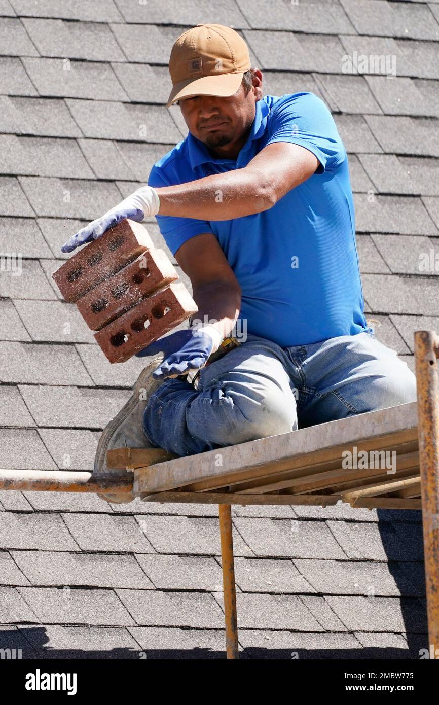 A mason catches three bricks tossed by a colleague, to lay on the top ...