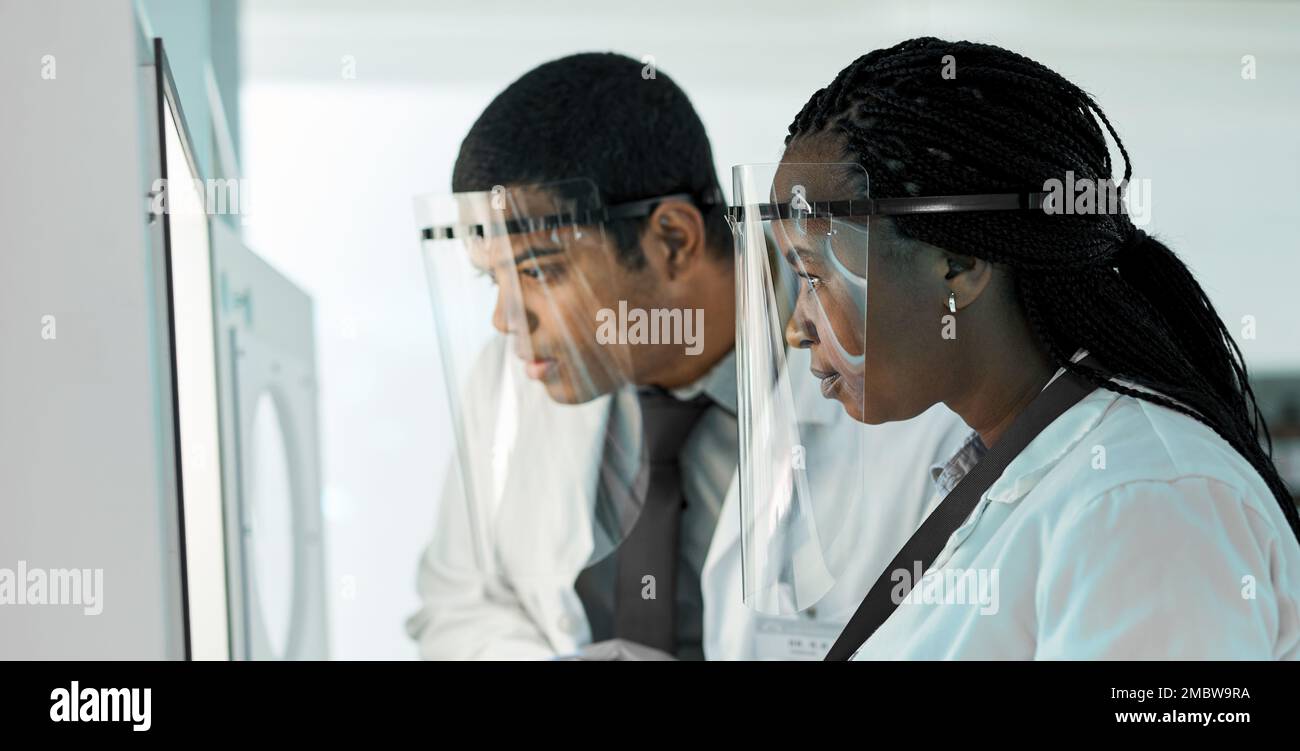 Getting down to lab work. two scientists wearing face shields while ...