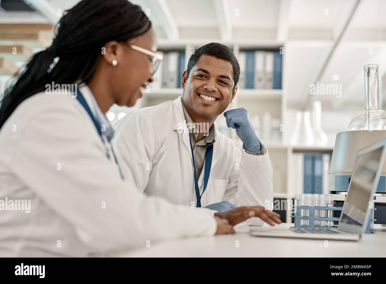 Making impactful discoveries together. two scientists working together on a laptop in a lab ...