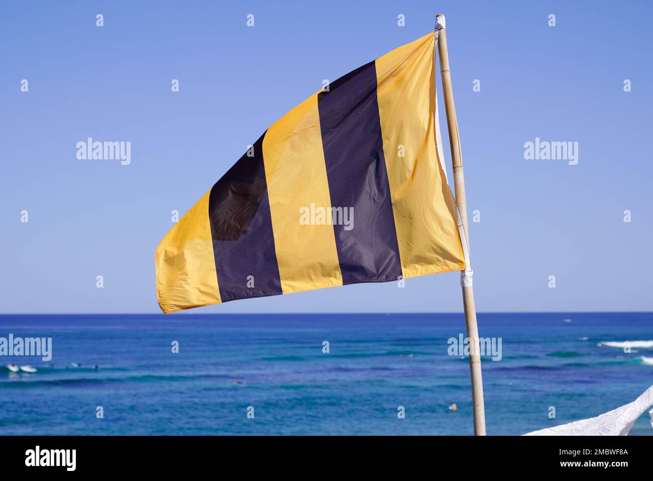 Warning flag yellow black vertical line waving on coast beach on sunny ...