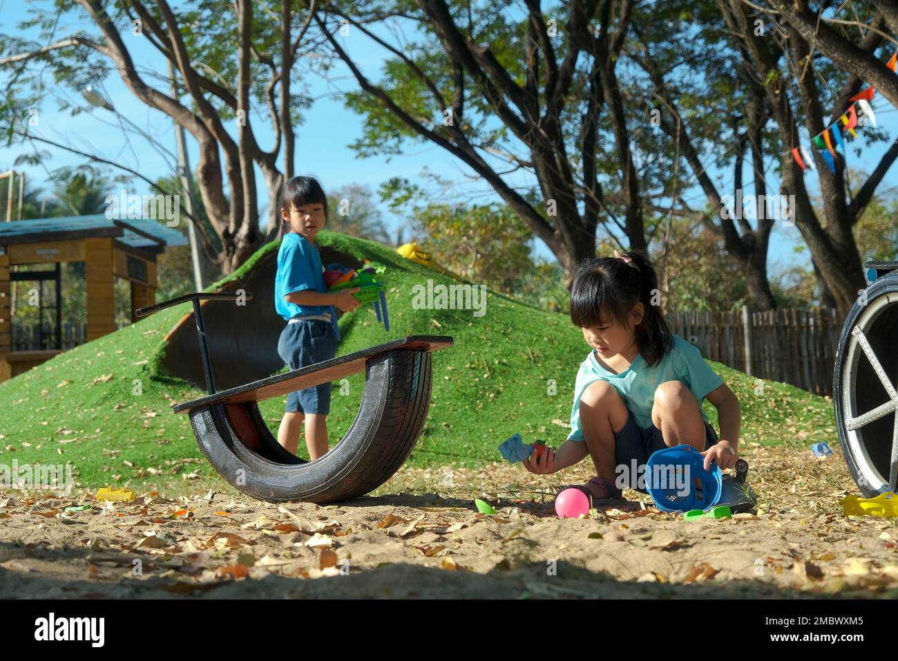 Cute sisters playing in the sandbox at the outdoor playground together ...