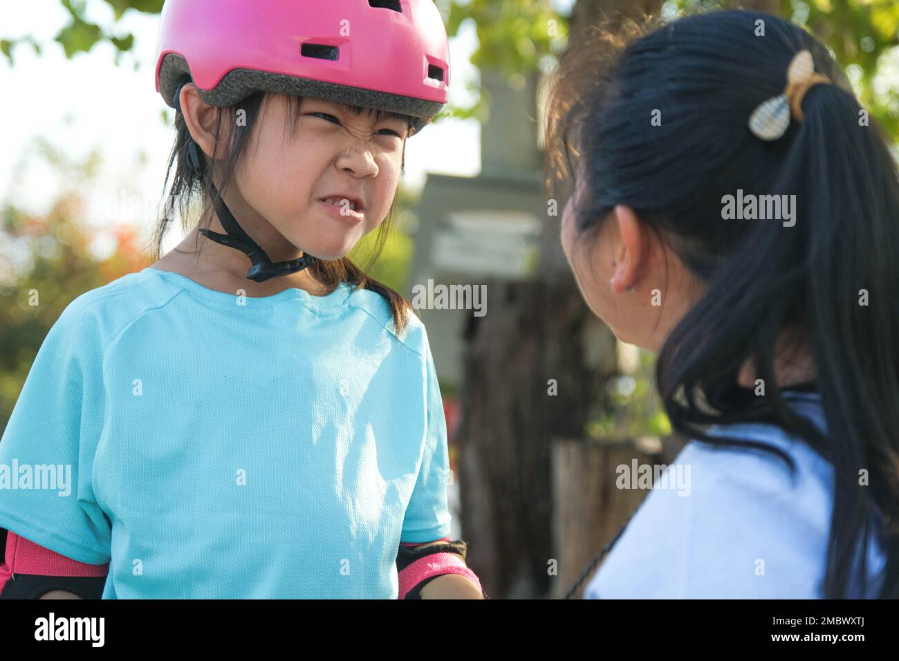 Young mother helps her daughter put on her protection pads and helmet ...