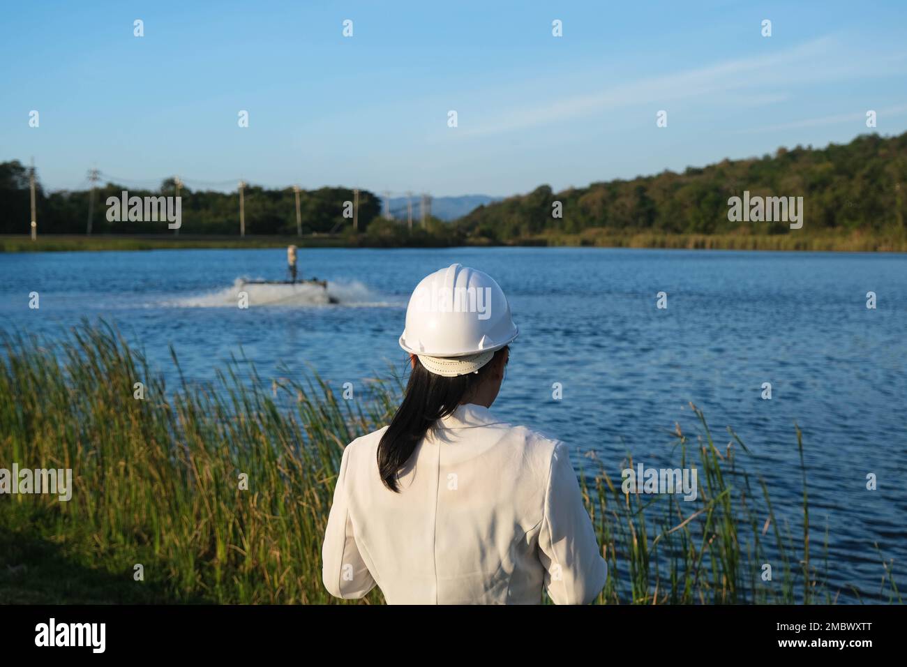 Environmental engineer wearing a white helmet uses a mobile phone to ...