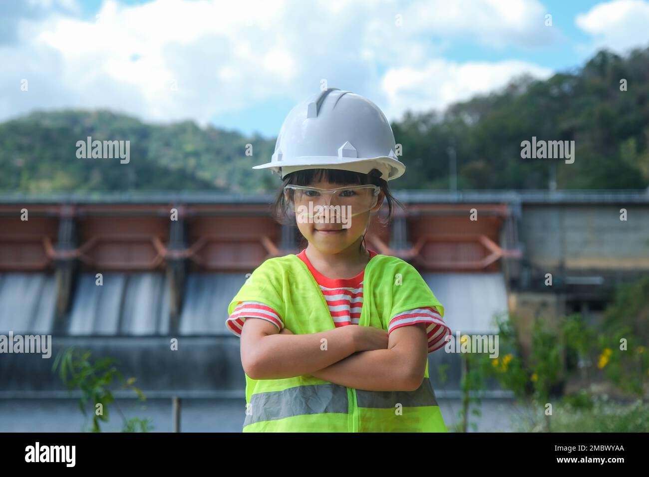 Portrait of a little girl engineer wearing a green vest and white ...