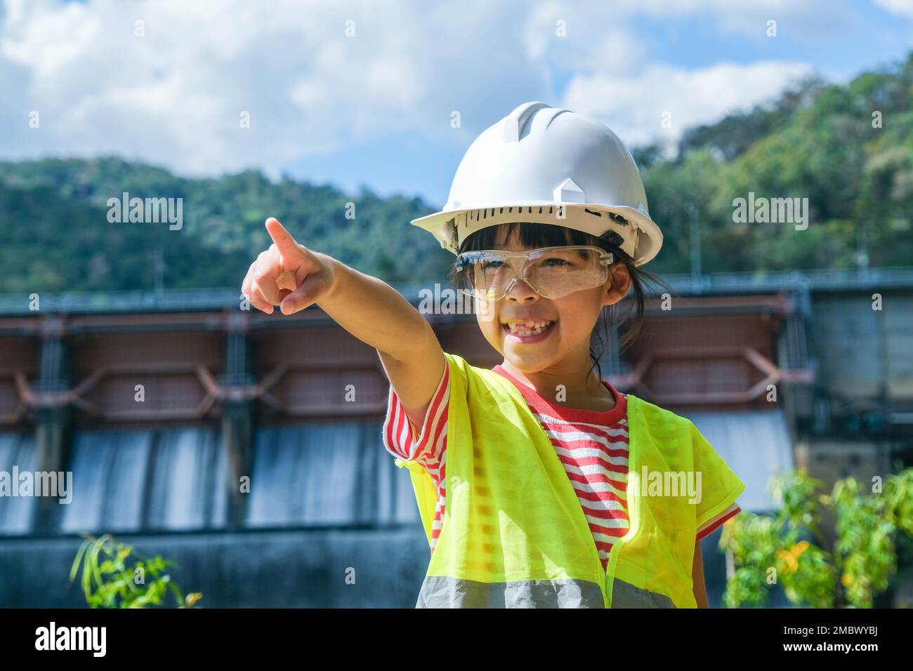 Portrait of a little girl engineer wearing a green vest and white ...