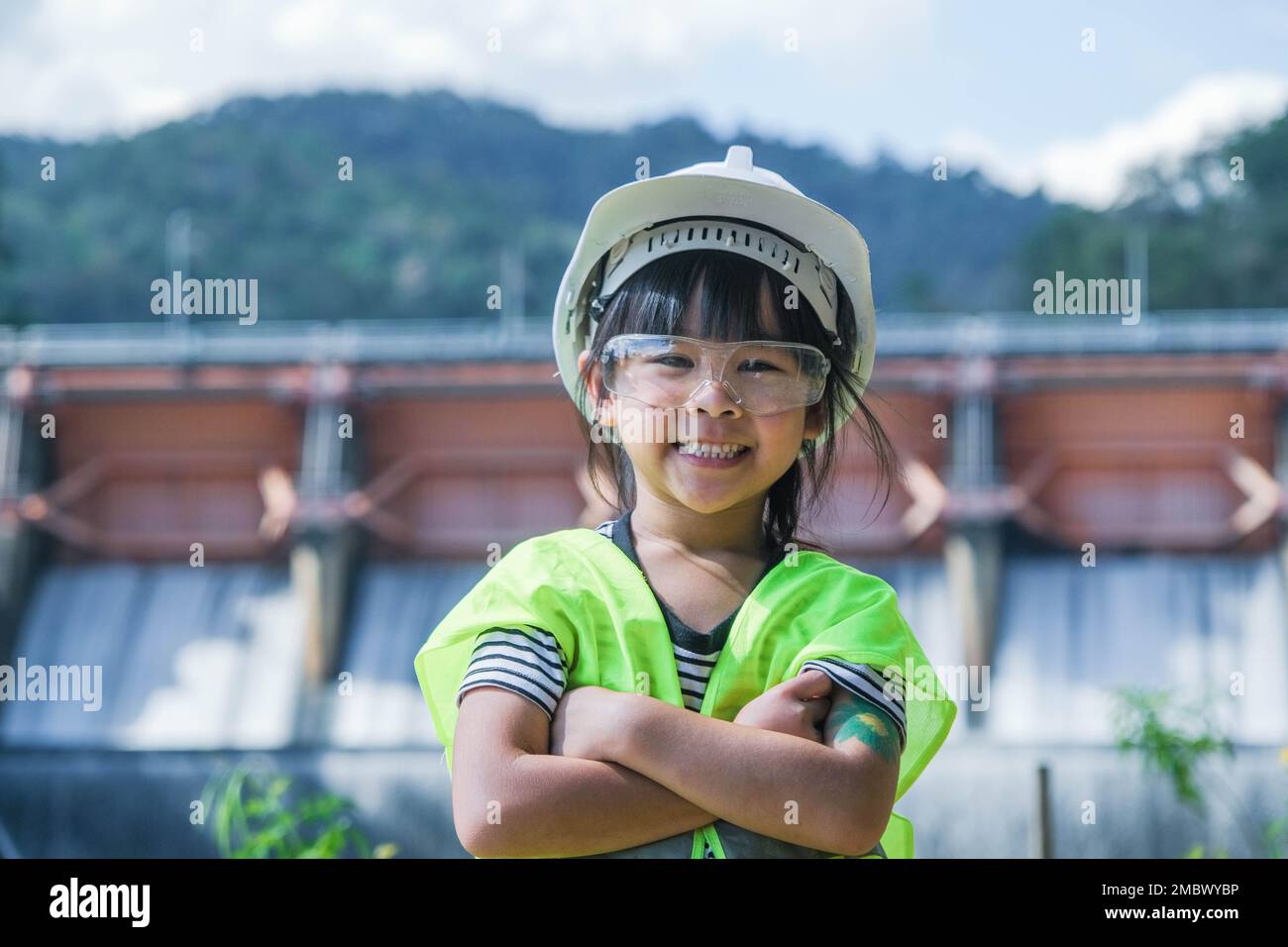 Portrait of a little girl engineer wearing a green vest and white ...