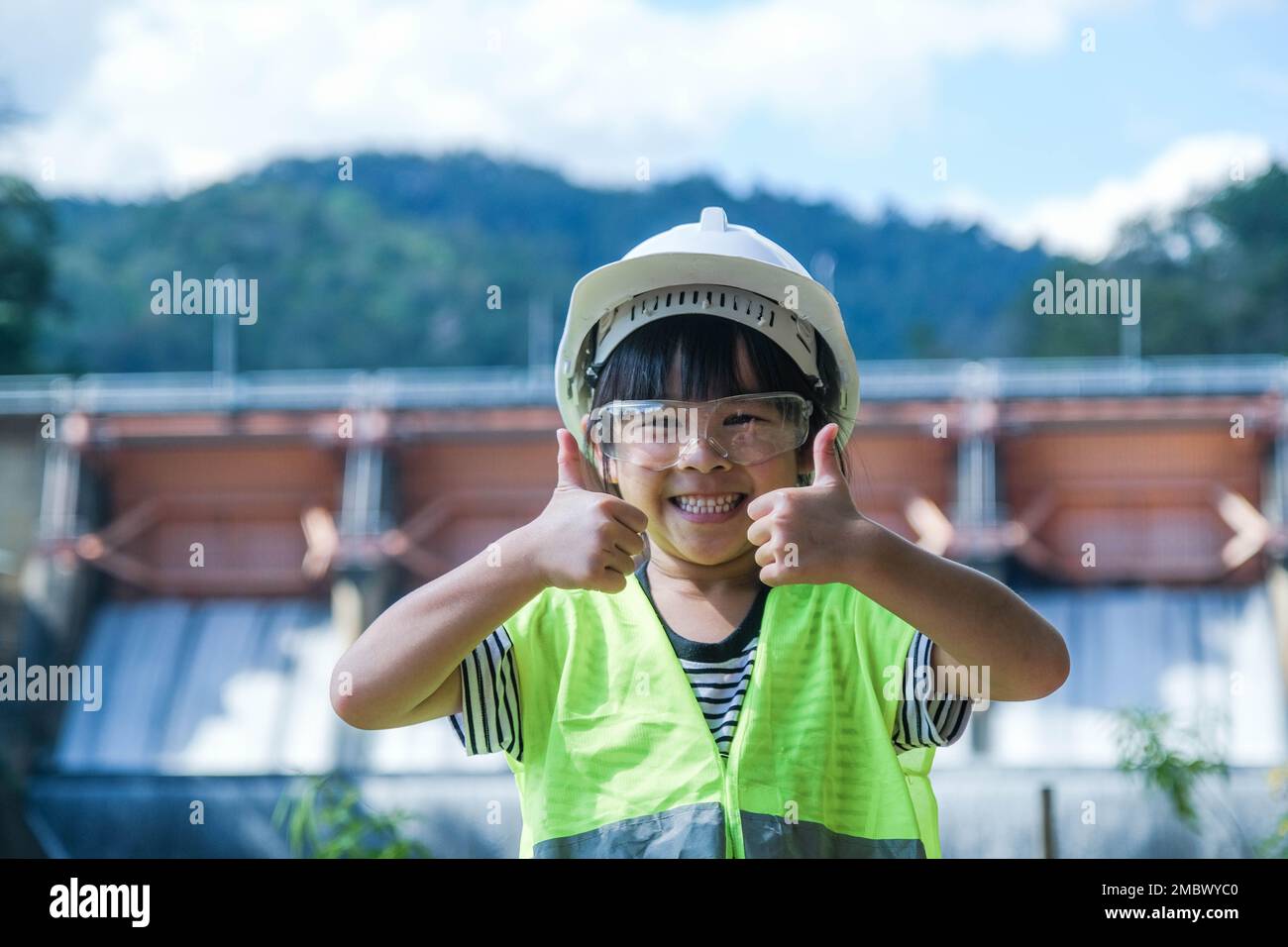 Portrait of a little girl engineer wearing a green vest and white ...