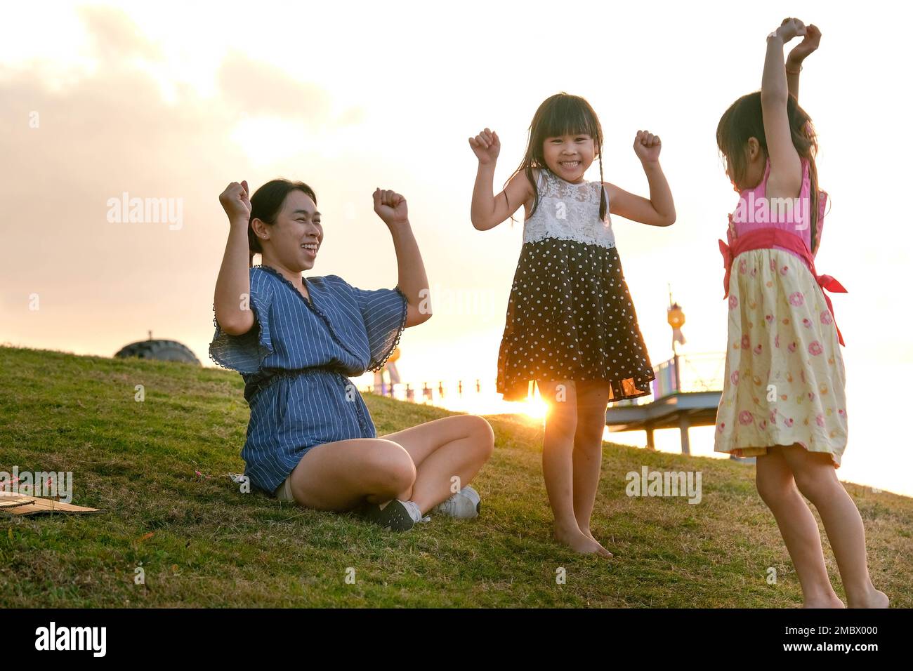 Active sisters playing at the park, running up a green grassy hill ...