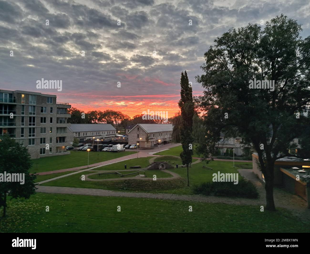 A summer garden and modern buildings before the red sunset on a summer ...