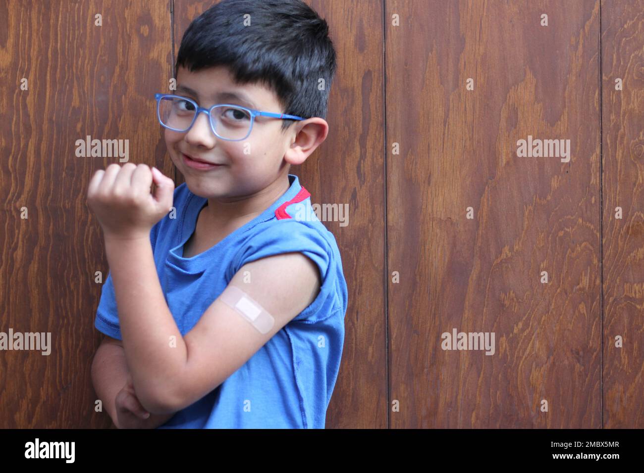 Little 6-year-old Latino boy with glasses and a blue shirt shows his ...