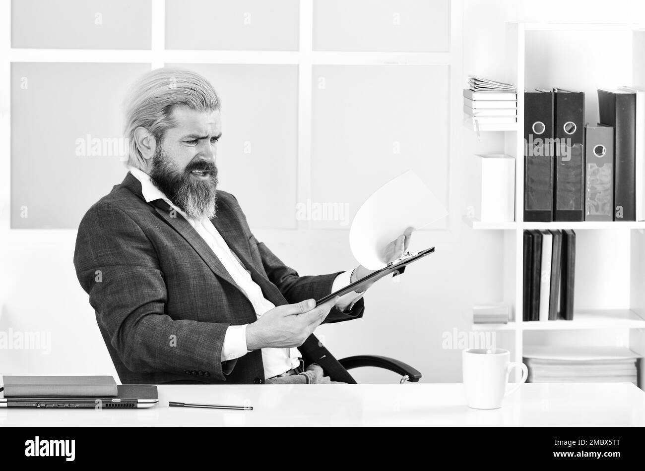 angry bearded man in formal jacket sit at table. boss in workplace ...