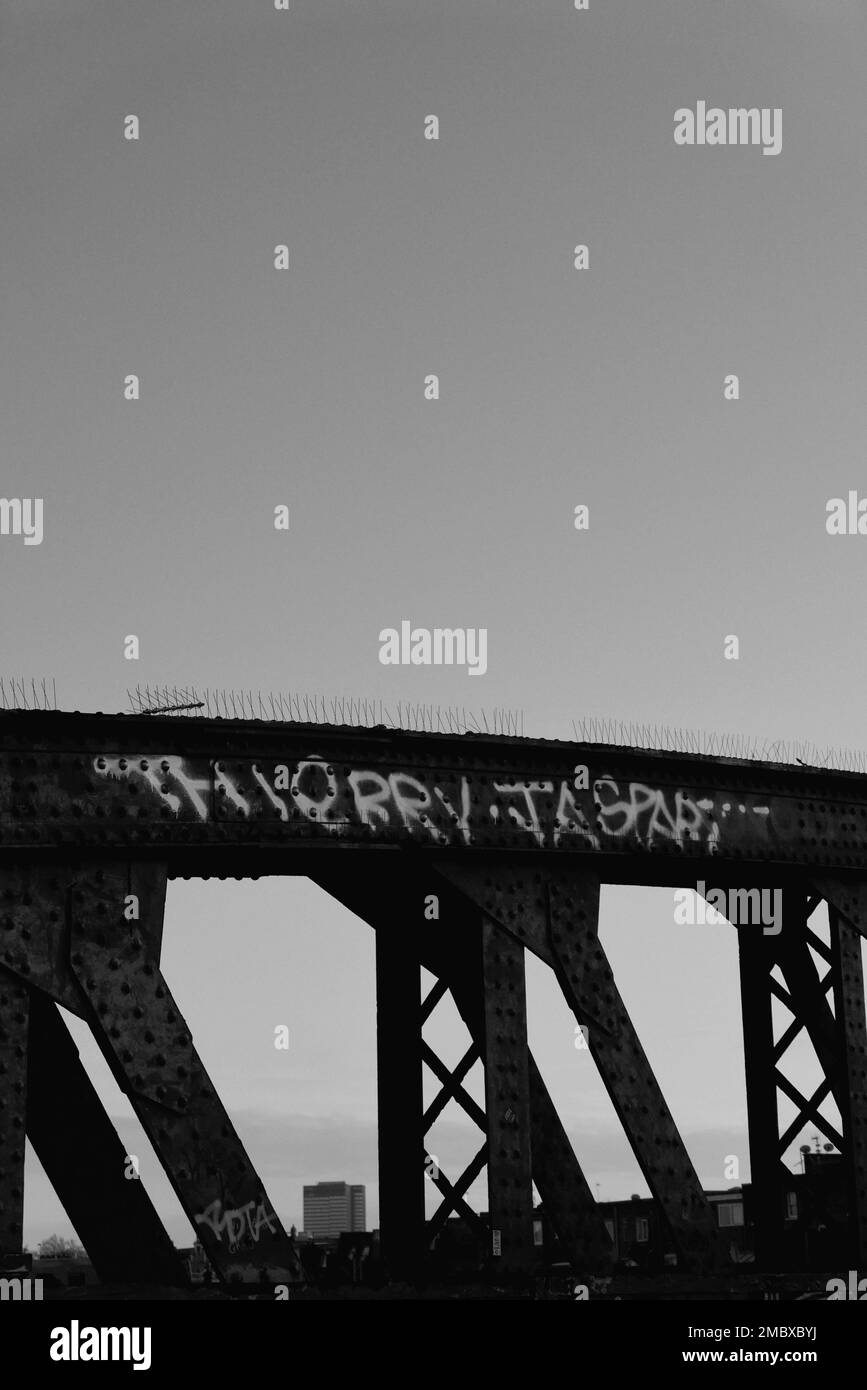 A vertical shot of a spray painted quote sign on a high metal bridge in ...