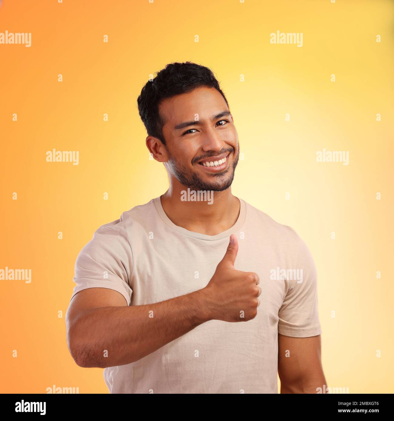Hands, thumbs up and portrait of man in studio isolated on a yellow ...