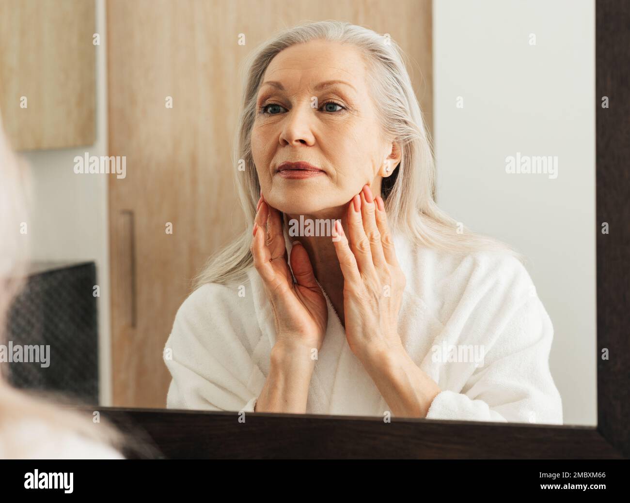 Senior woman stretching skin on her face in front of a mirror Stock ...