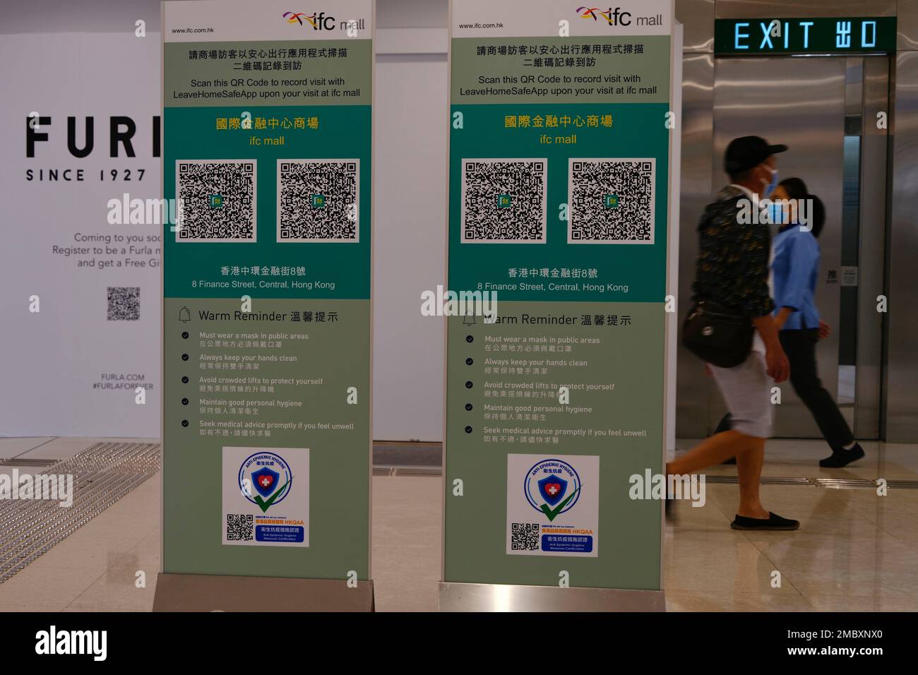 People wearing face masks walk past QR codes at a shopping mall in Hong ...