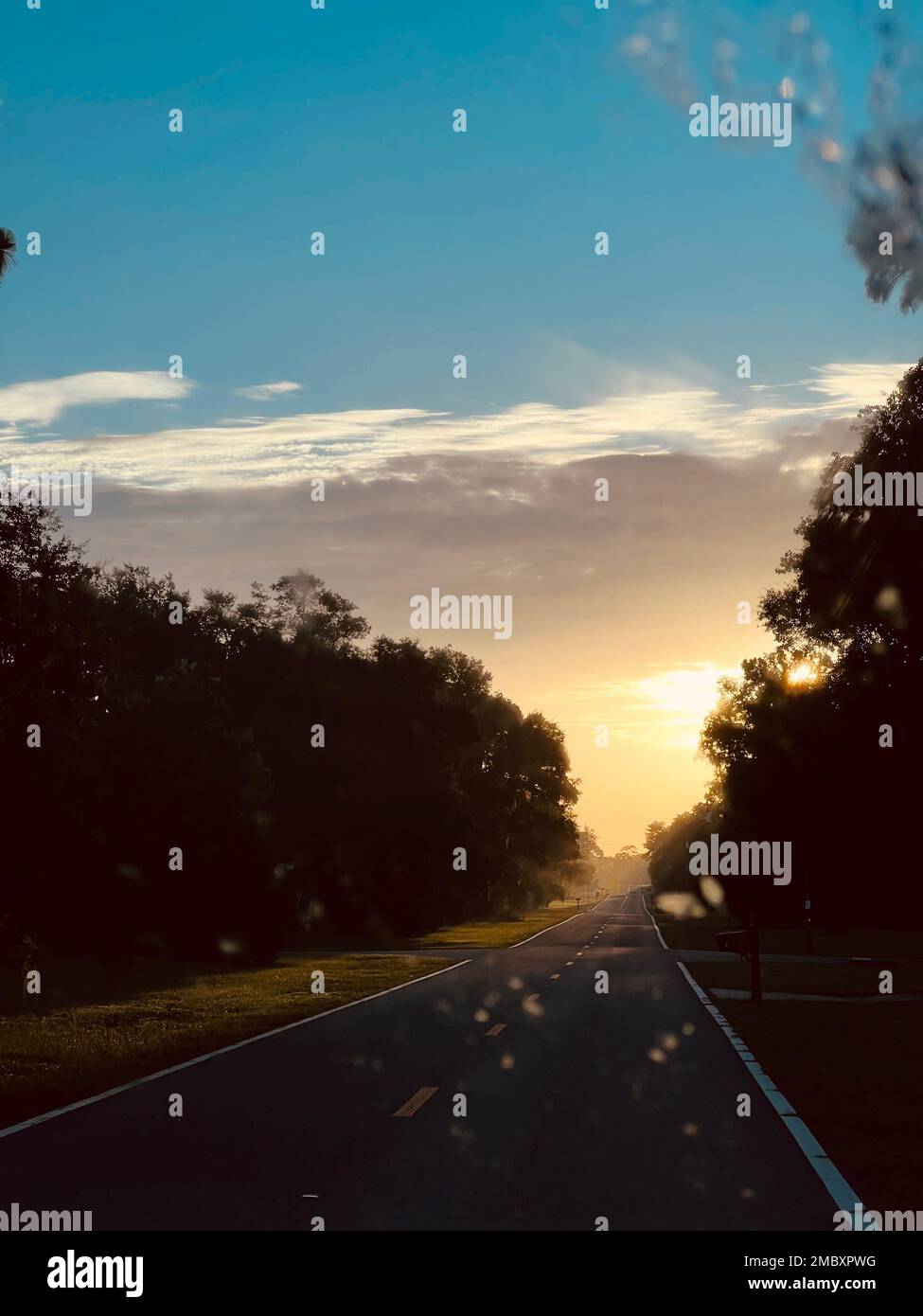 A scenic view of an asphalt road under a sunset sky Stock Photo - Alamy
