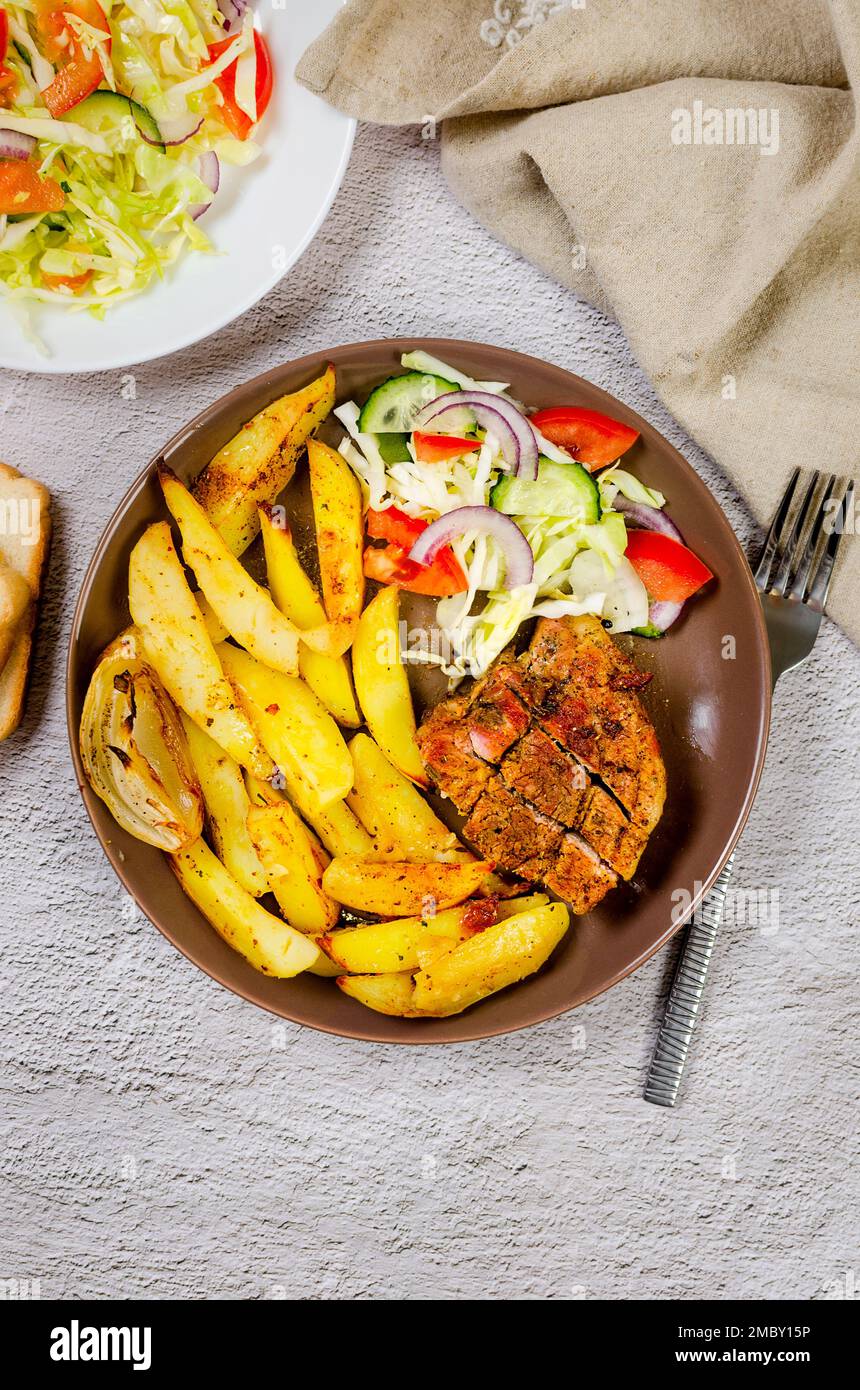 fried ribs with baked potatoes and spices on plate for tasty lunch ...