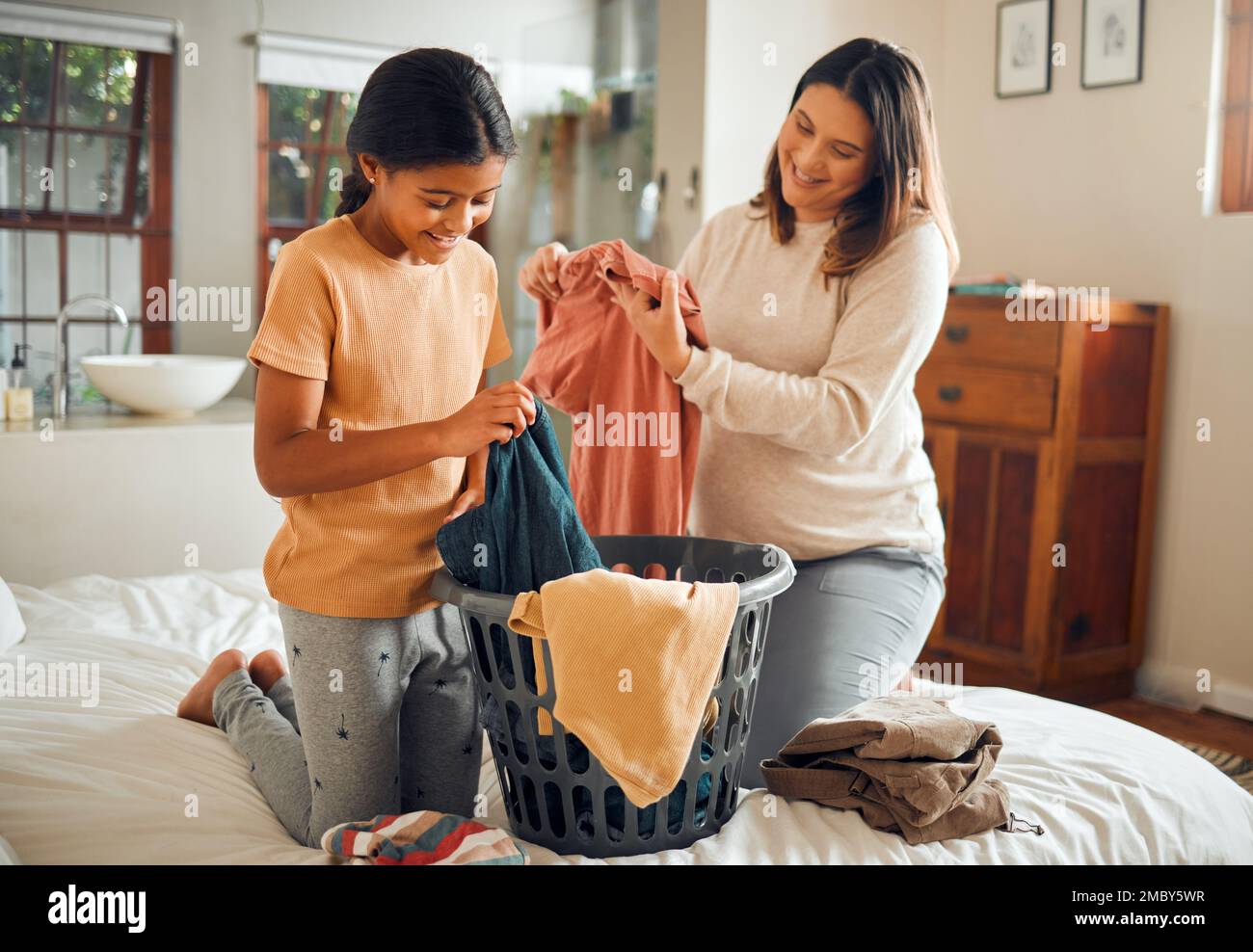 Laundry, happy mother and child help with house cleaning for pregnant mom with love and care ...