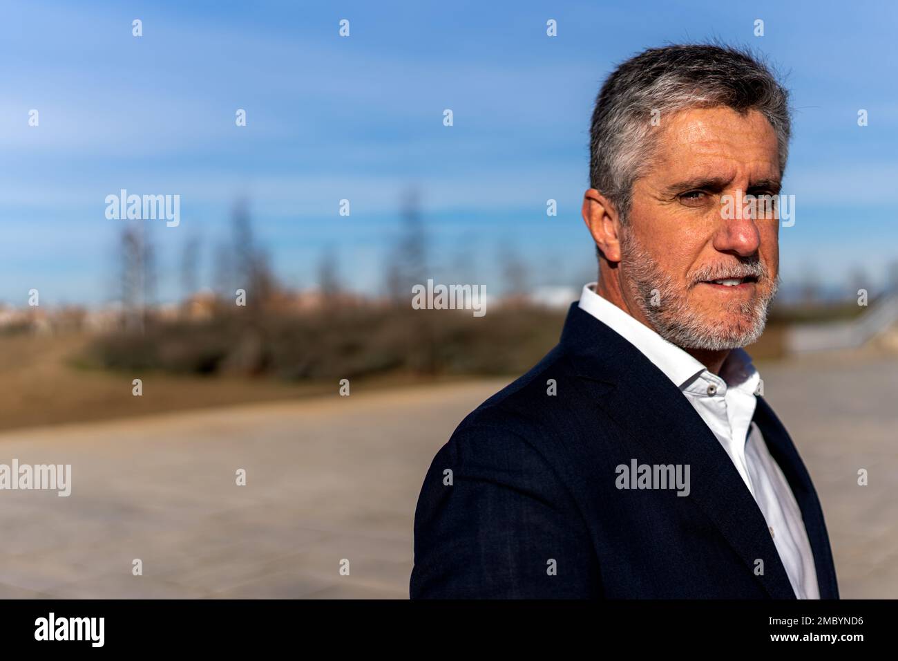 Pensive senior businessman in formal wear looking at camera while ...