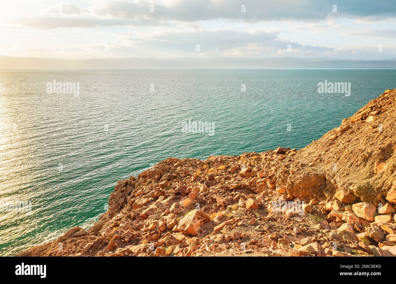 Dead sea shore at Jordan side, dry sand and rocks beach, sun shines on ...
