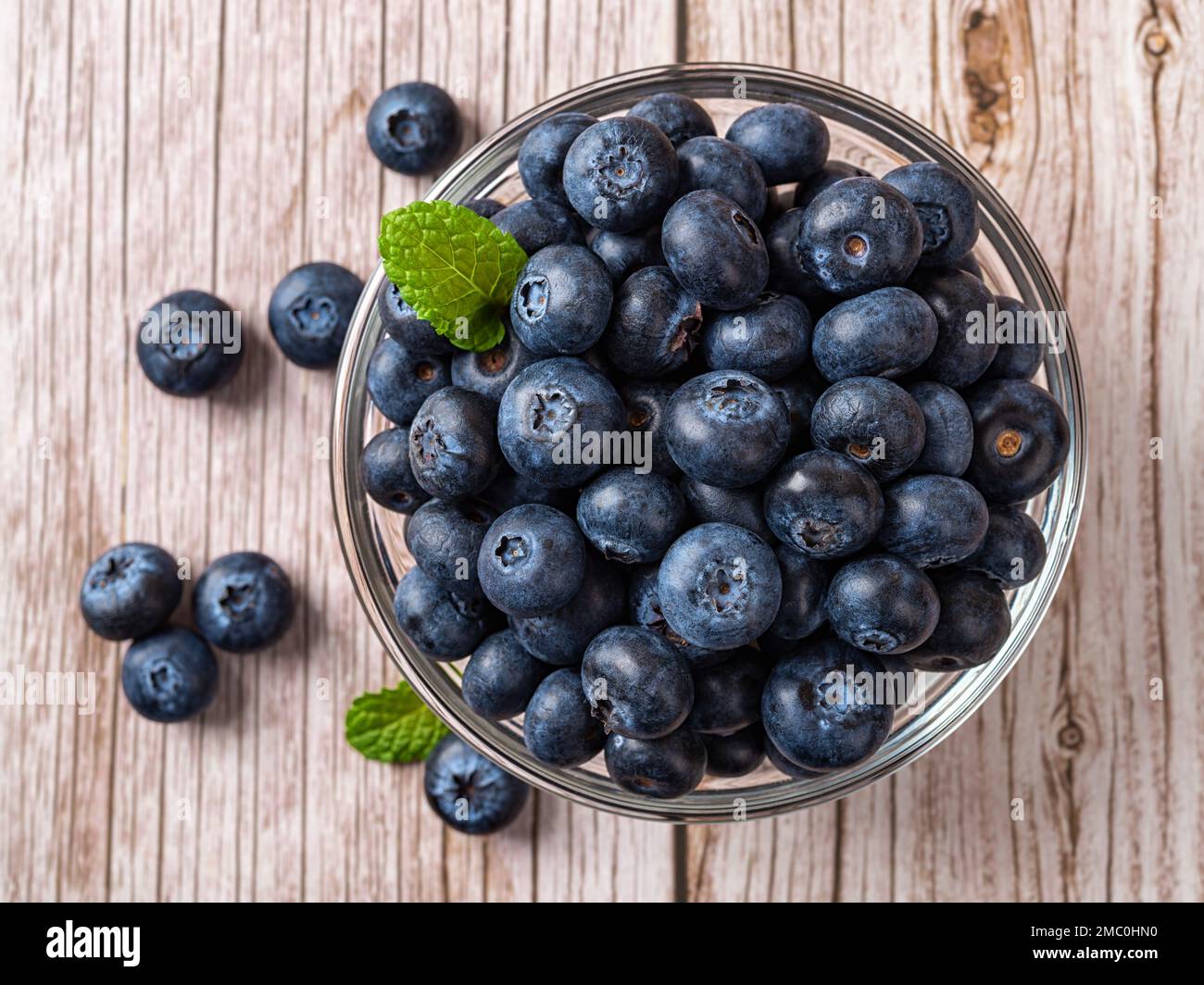 Sweet blueberries in a glass bowl over wooden surface. Ripe juicy wild ...