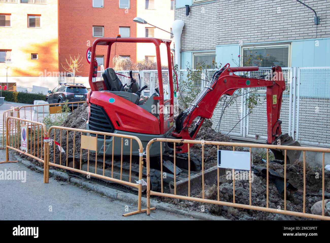 mini Backhoe stopped, inside a fenced enclosure, on the construction ...