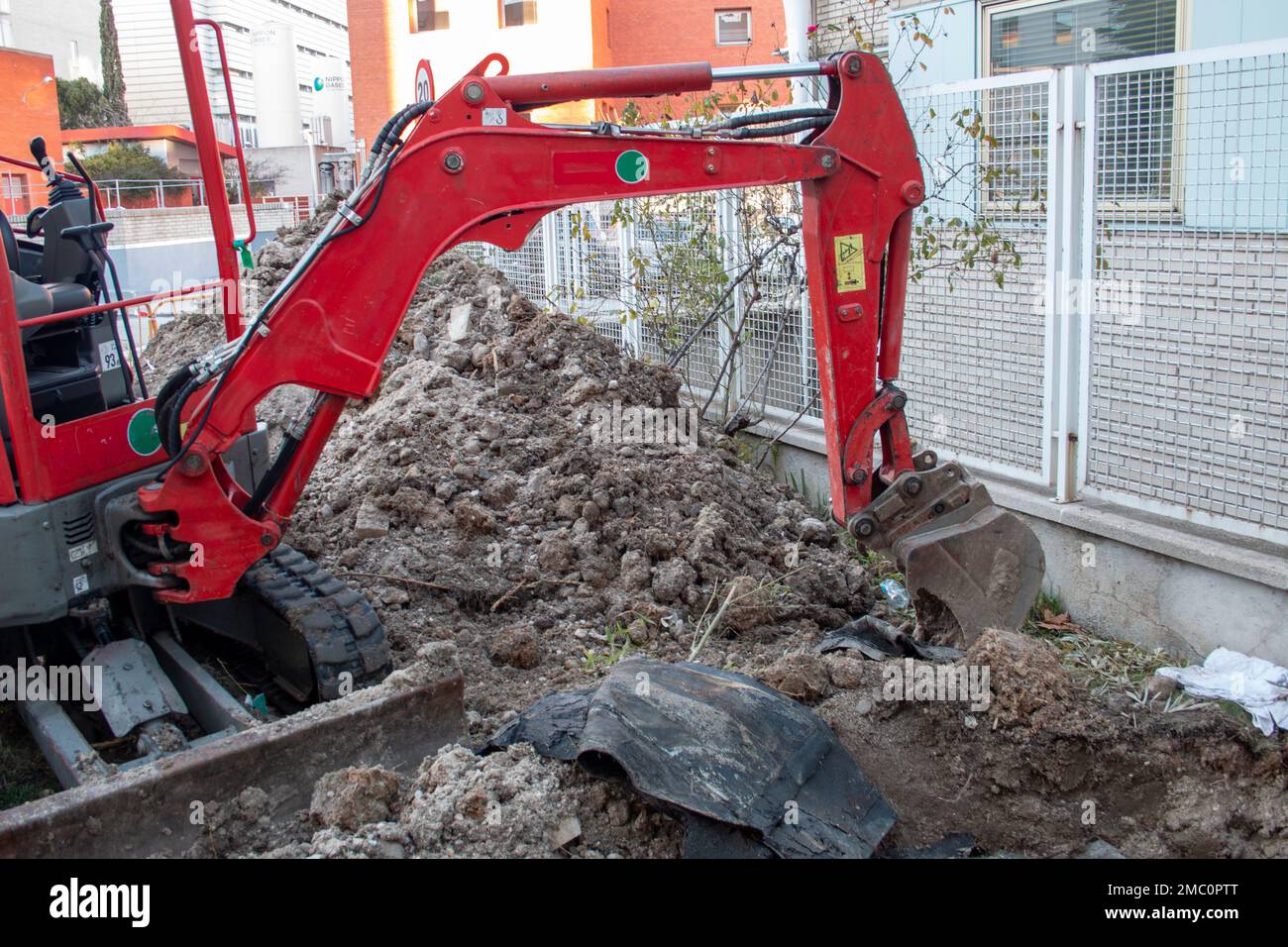 mini Backhoe stopped, inside a fenced enclosure, on the construction ...