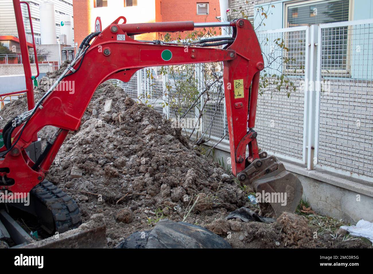 mini Backhoe stopped, inside a fenced enclosure, on the construction ...
