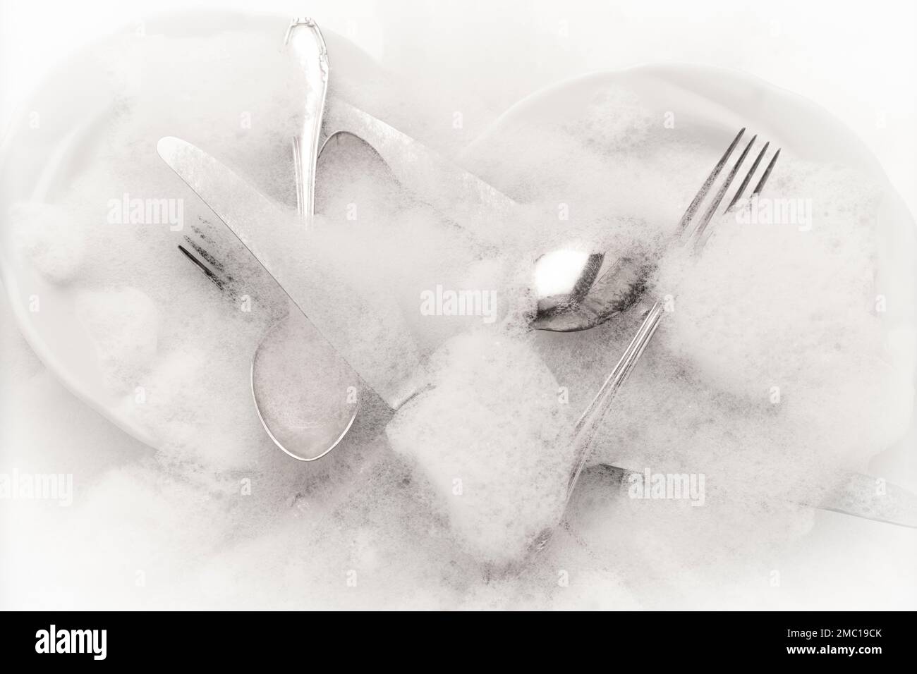Freshly washed crockery and cutlery in soapy water Stock Photo - Alamy